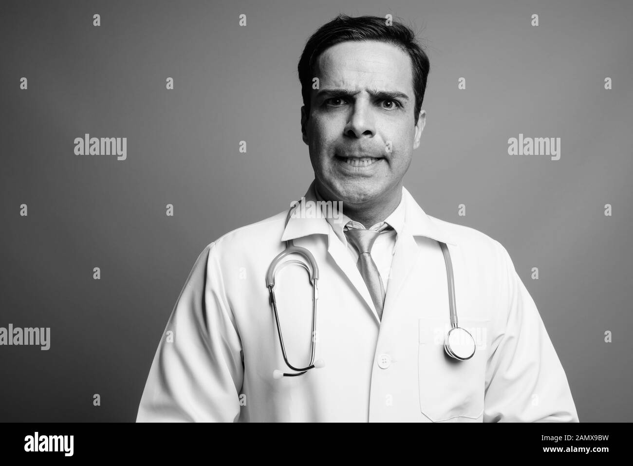 Handsome Persian man doctor against gray background Stock Photo - Alamy