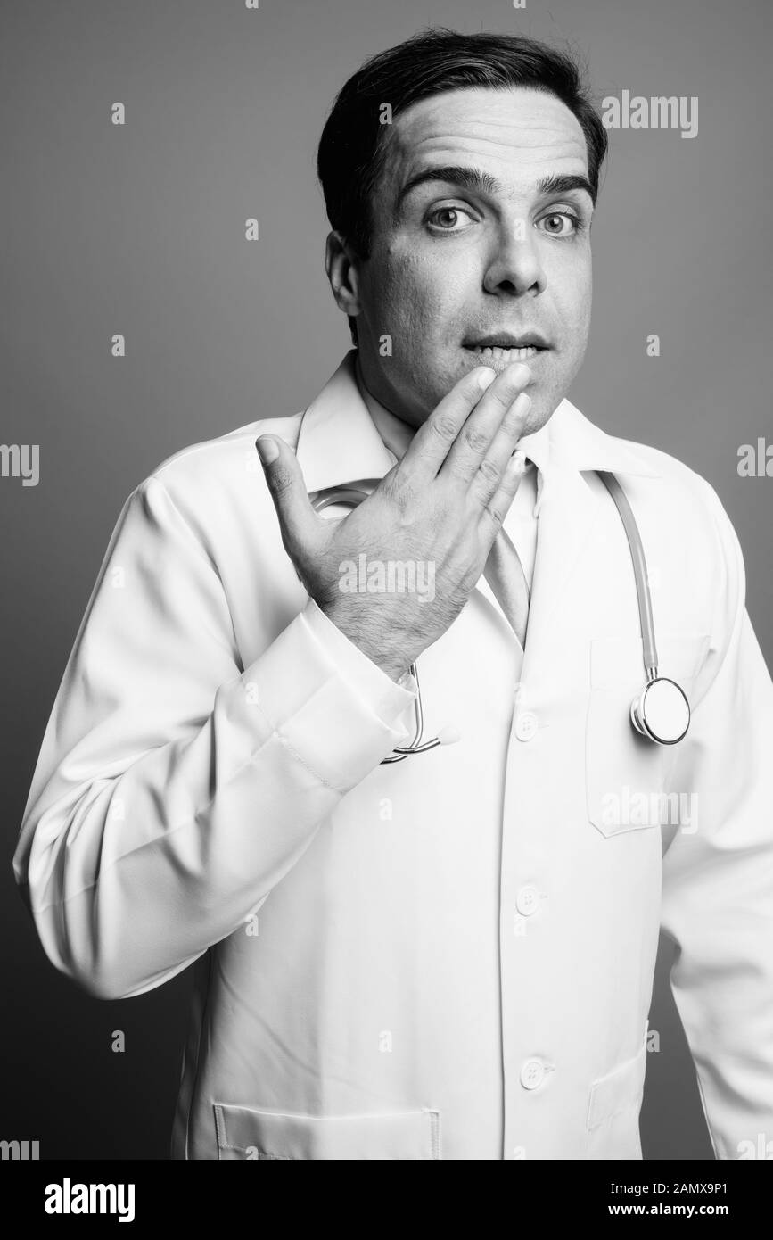 Handsome Persian man doctor against gray background Stock Photo - Alamy
