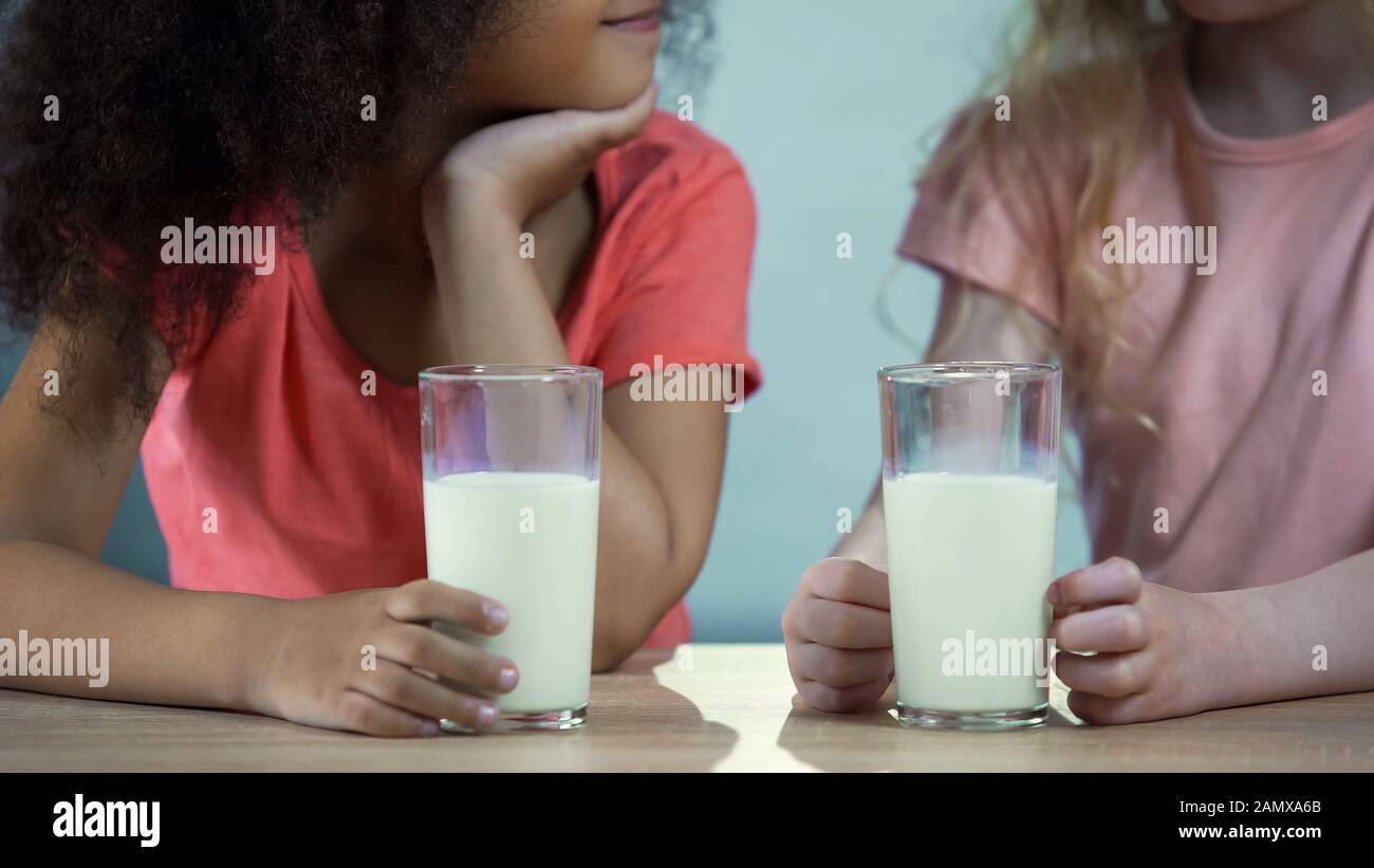 Multi-ethnic kids drinking milk and smiling to each other, healthy ...