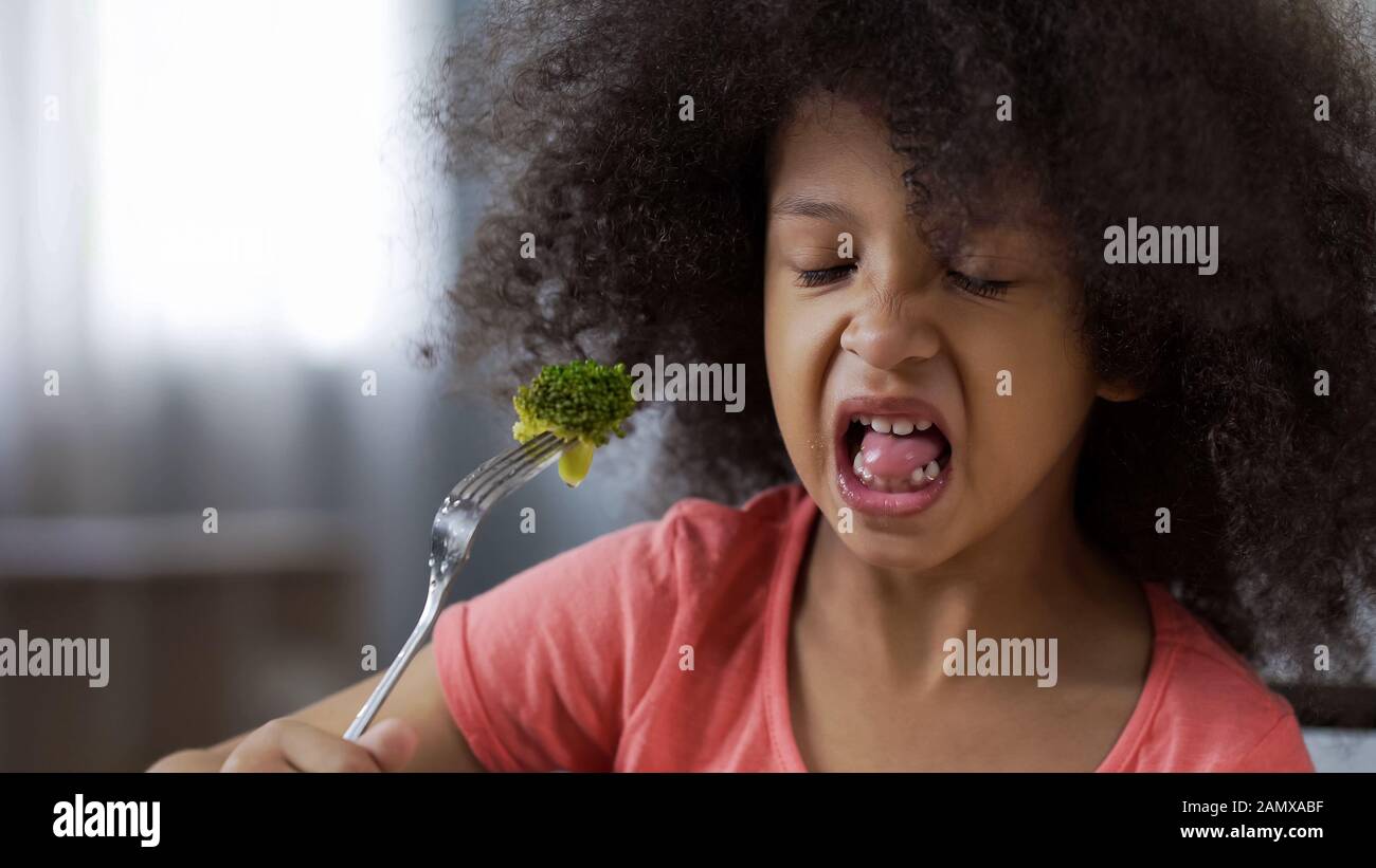 Funny African girl eating broccoli with huge disgust, healthy diet for ...