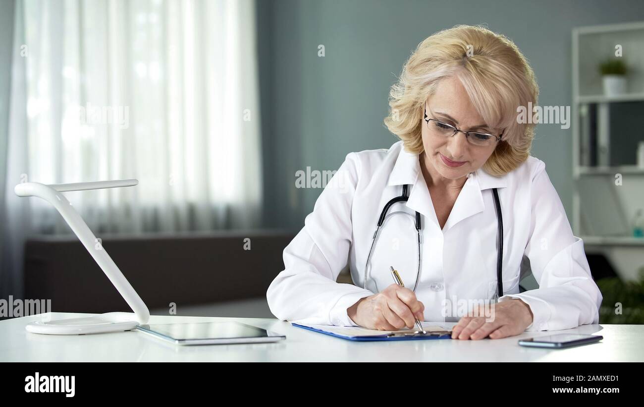 Lady doctor filling in health insurance form before proceeding to treat ...