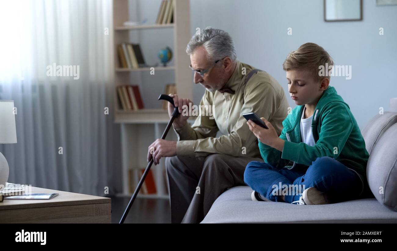 Boy using cell phone, upset granddad sitting aside, internet addiction ...