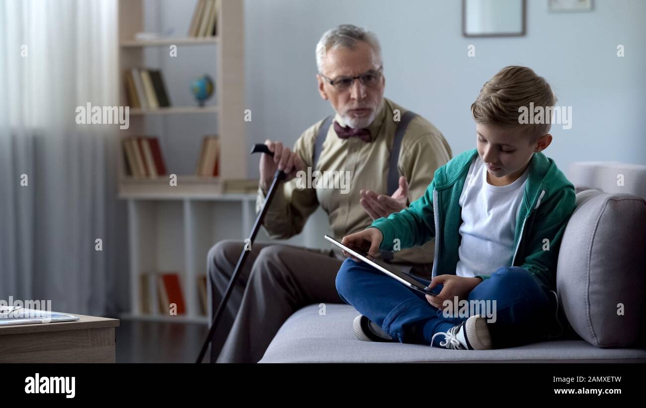 Angry grandpa scolding grandson for playing video game on tablet ...