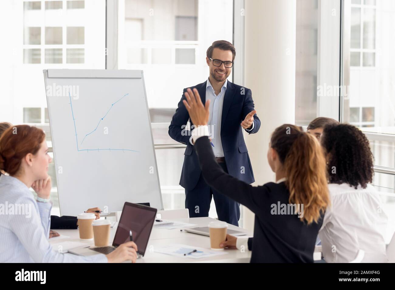 Female employee raise hand answering at work office training Stock ...