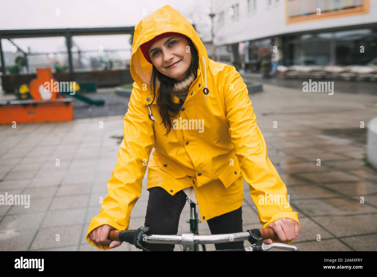 Girl in yellow raincoat riding bicycle on rain day Stock Photo - Alamy