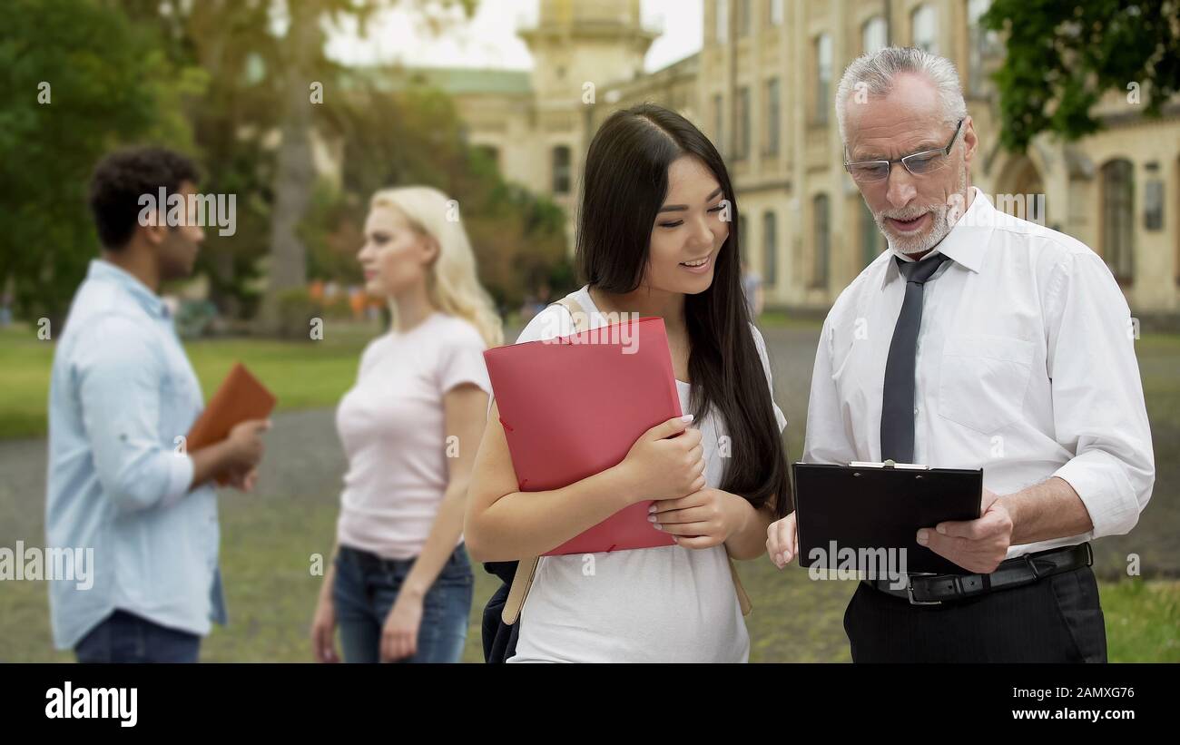 Male professor discussing thesis with asian female student near ...
