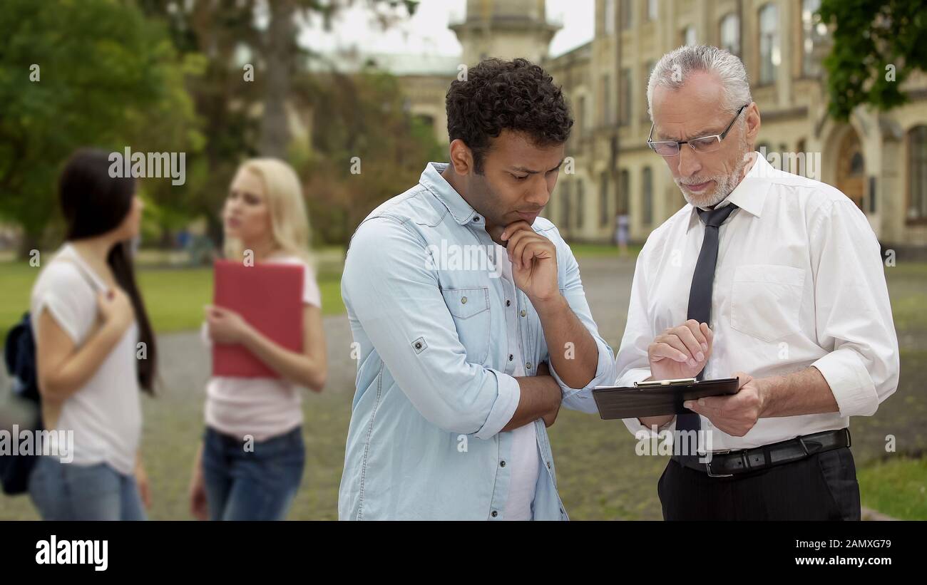 Math teacher explaining difficult task to puzzled male student near ...