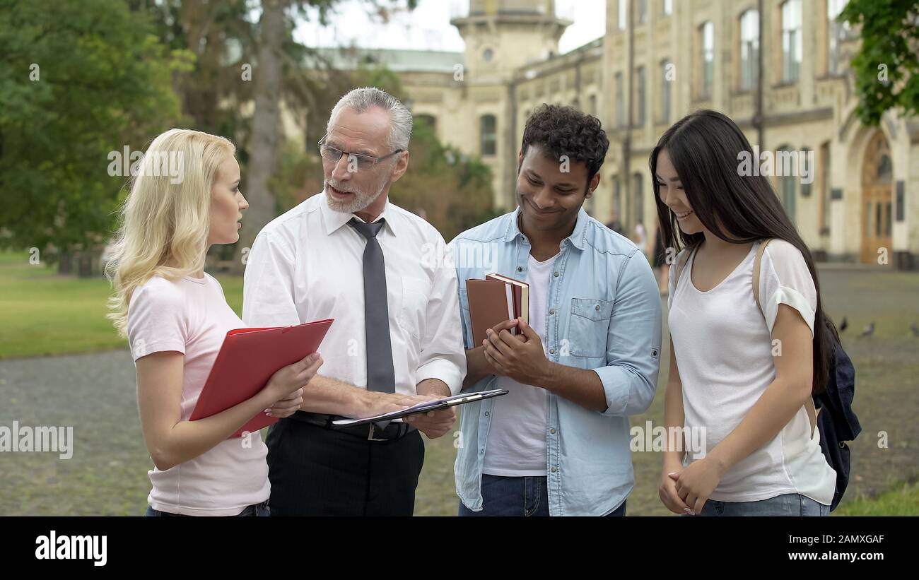 Physics teacher discussing scientific research with group of students ...