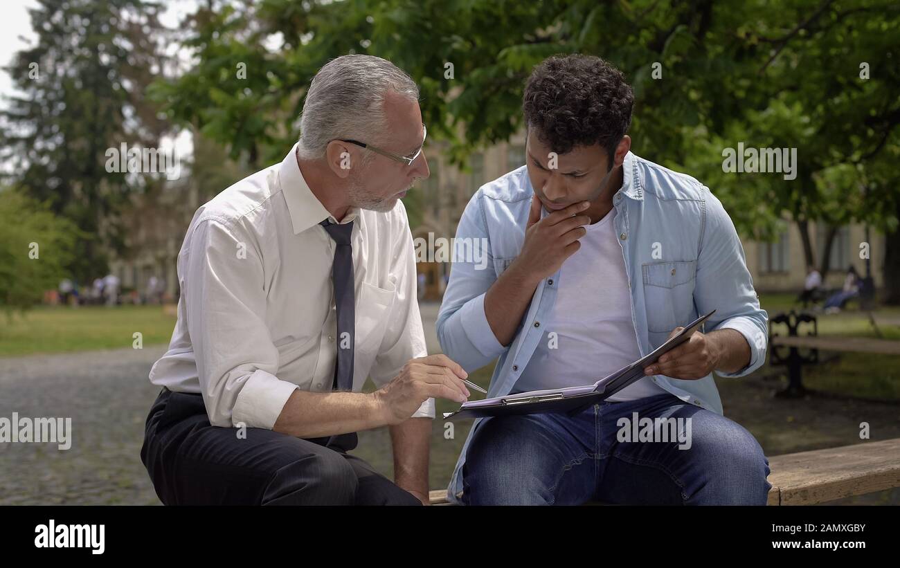 Teacher and smart Hispanic student discussing science project near ...