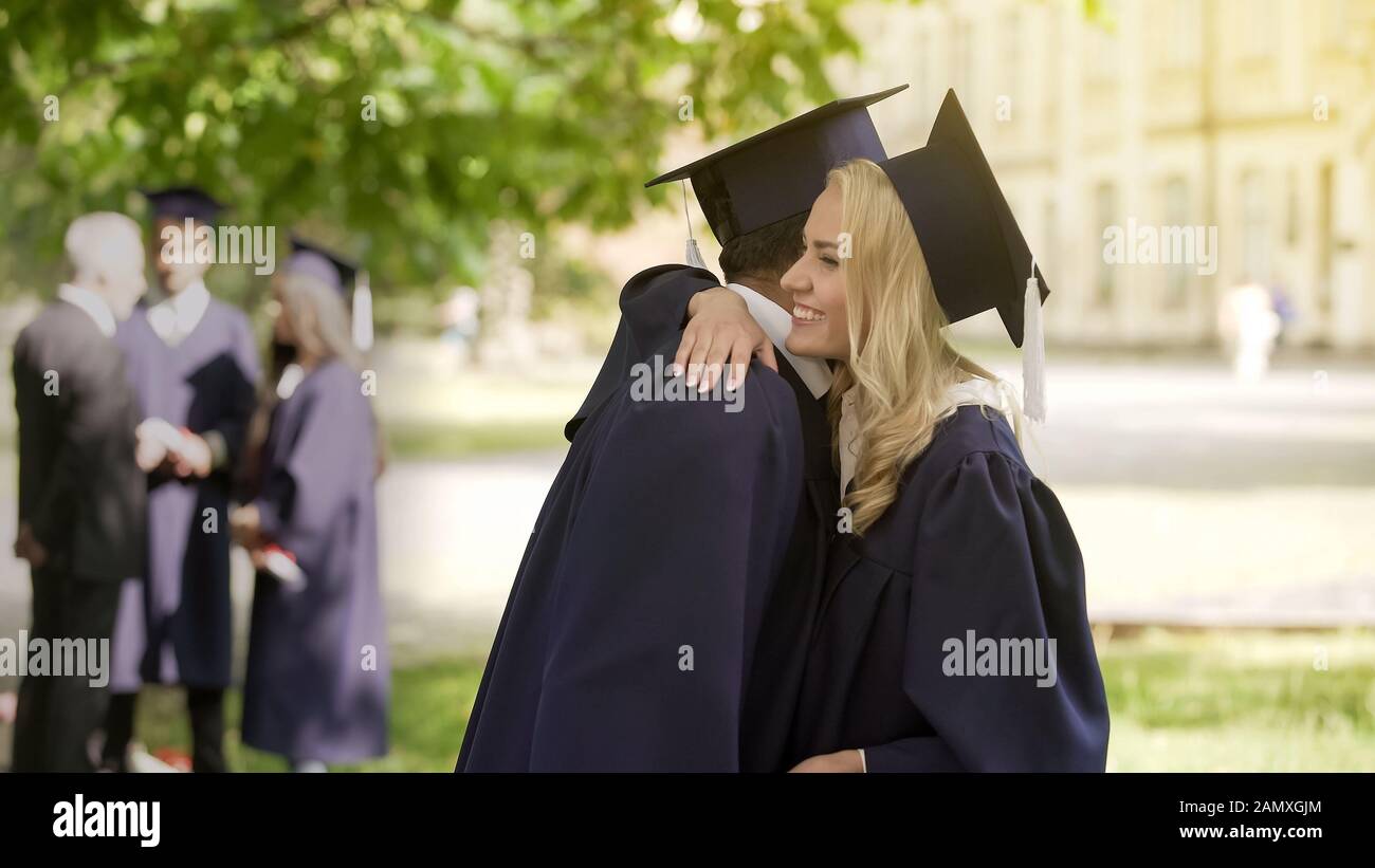 Classmates in graduation outfit talking, hugging and congratulating ...
