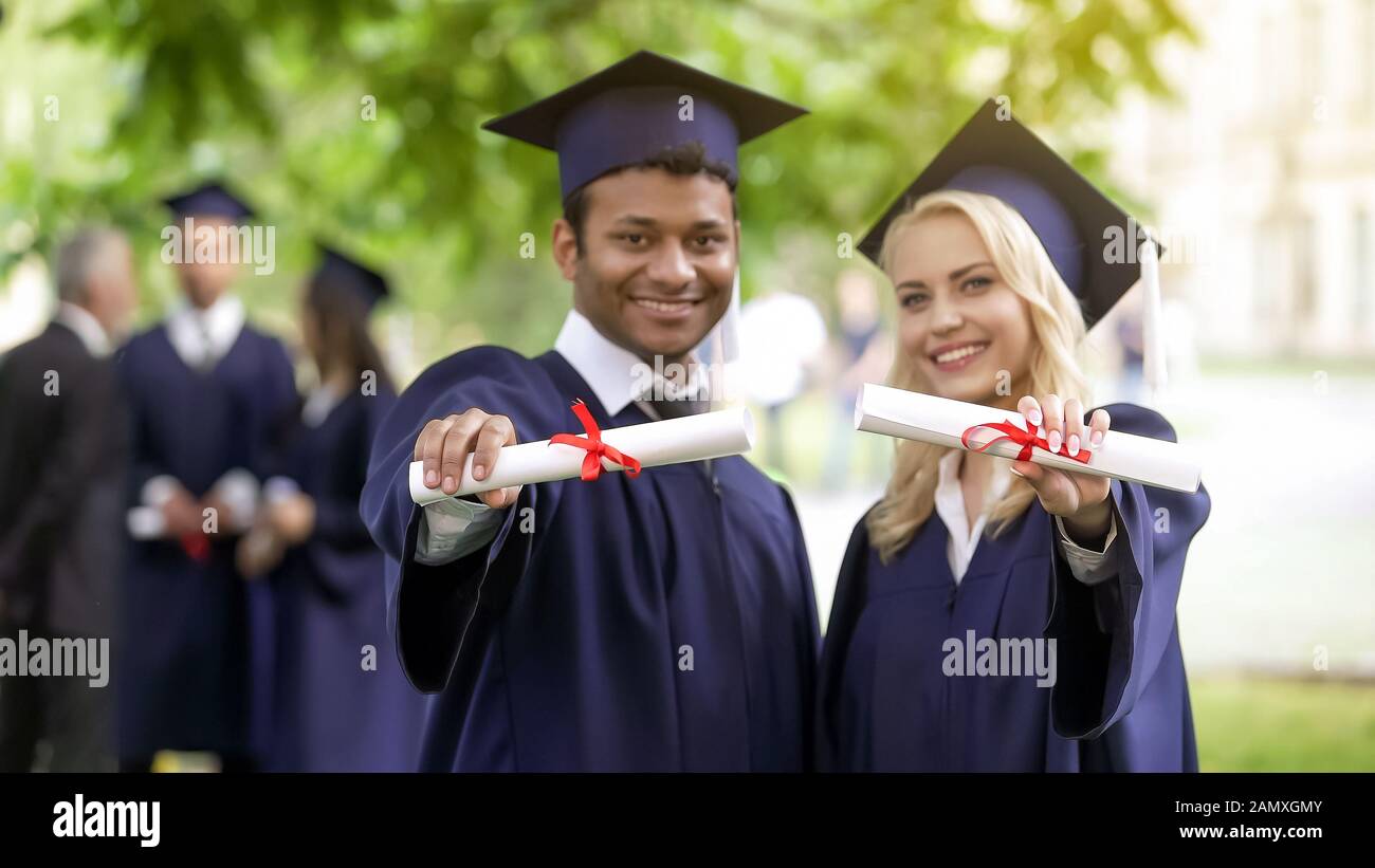 Happy couple of graduates showing diplomas and smiling, complete high ...