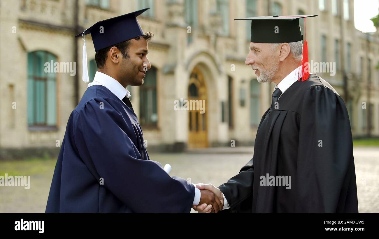 Eminent professor giving diploma to male student shaking hand ...