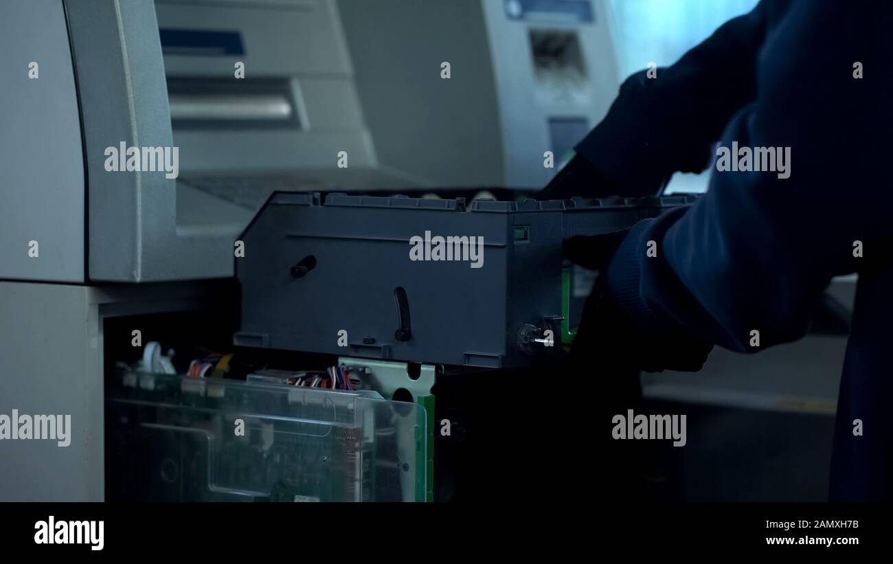 Robber wearing gloves stealing money from ATM cases at nighttime ...