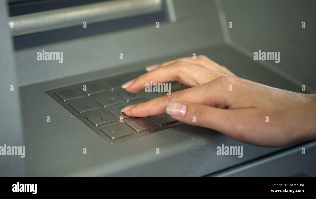Woman entering PIN number to check bank account and withdraw money from ...