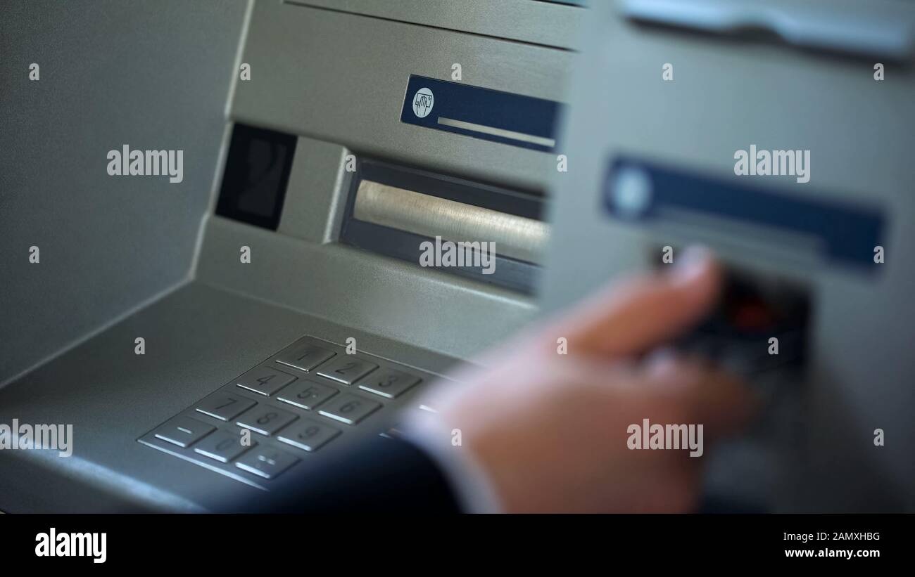 Man in suit finishing banking transaction, removing card from ATM ...