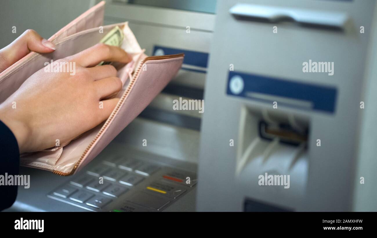 Female hands putting dollars in wallet, cash withdrawn from ATM ...