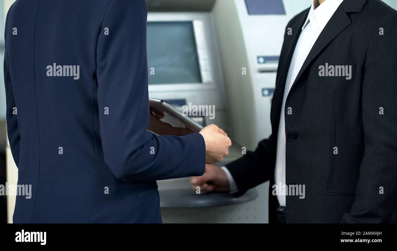 Banker showing client on tablet how to pay utility bill online and ...