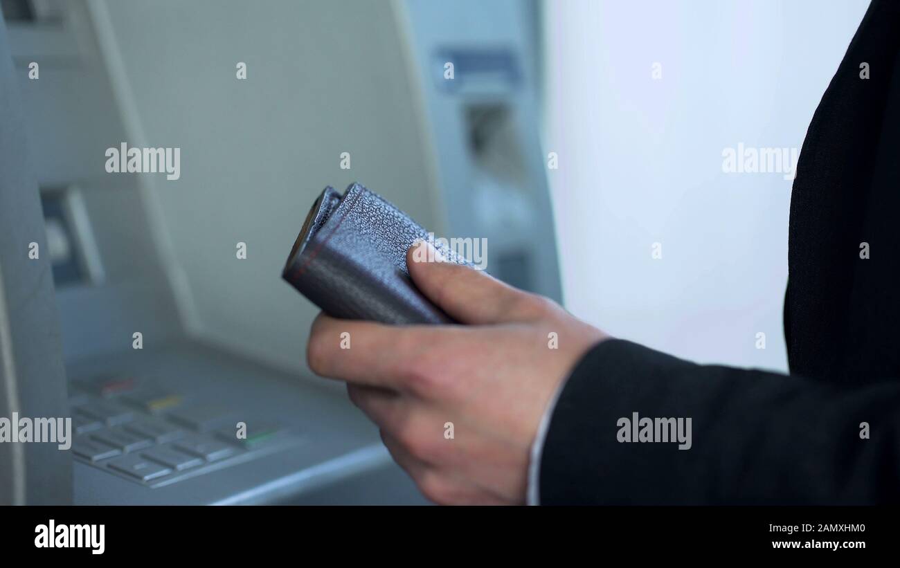 Man with wallet typing pin code on ATM to withdraw money and check ...