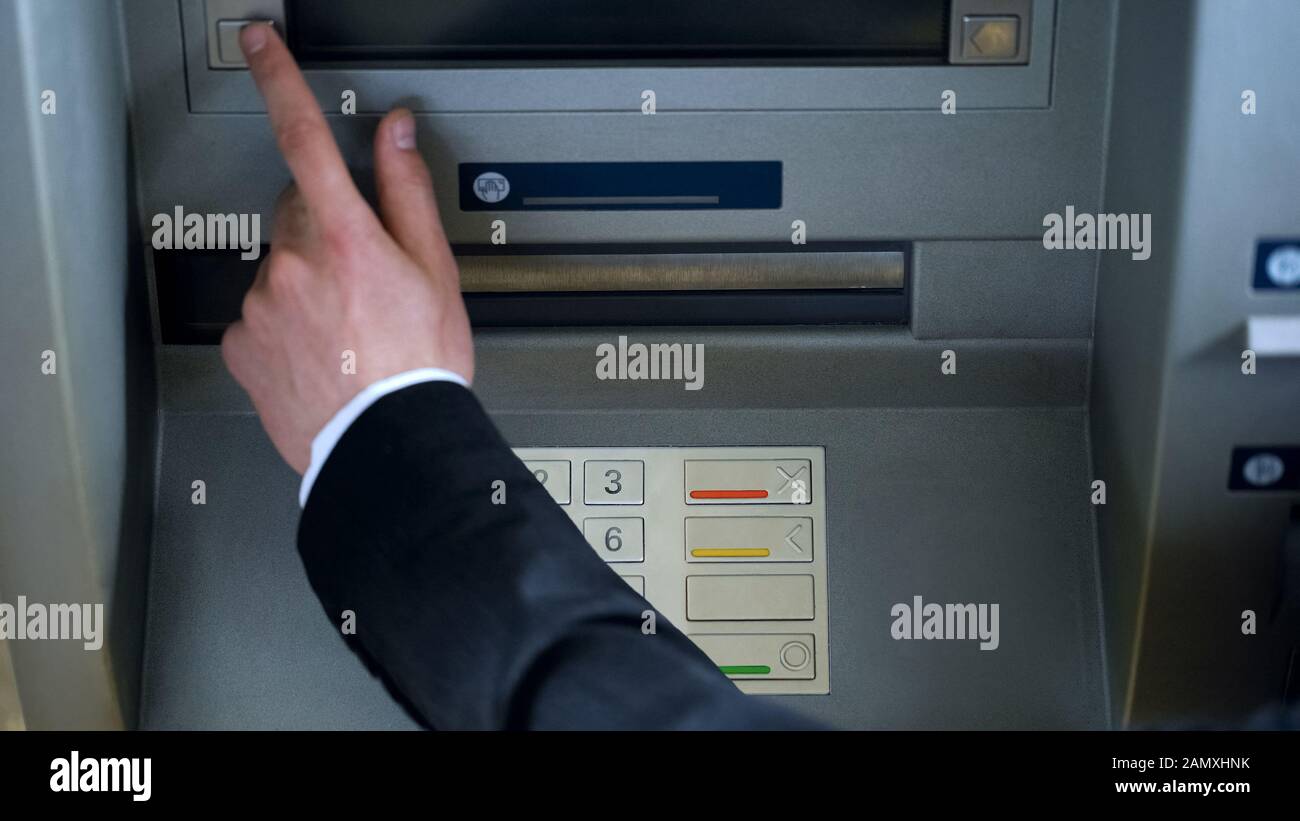 Mans hand pressing button on display screen of ATM machine, bank ...