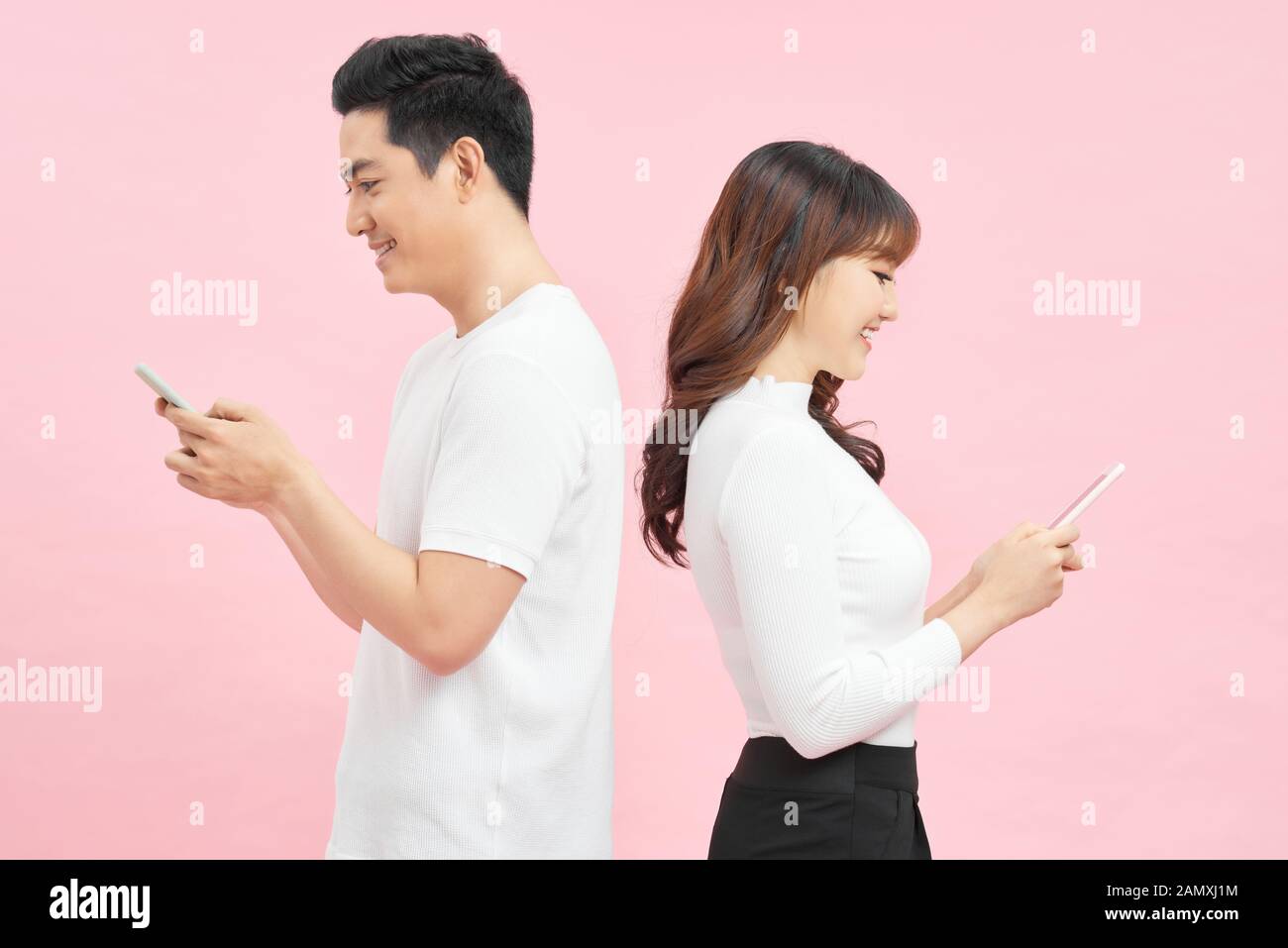 Romantic messages. Beautiful young loving couple holding mobile phones ...