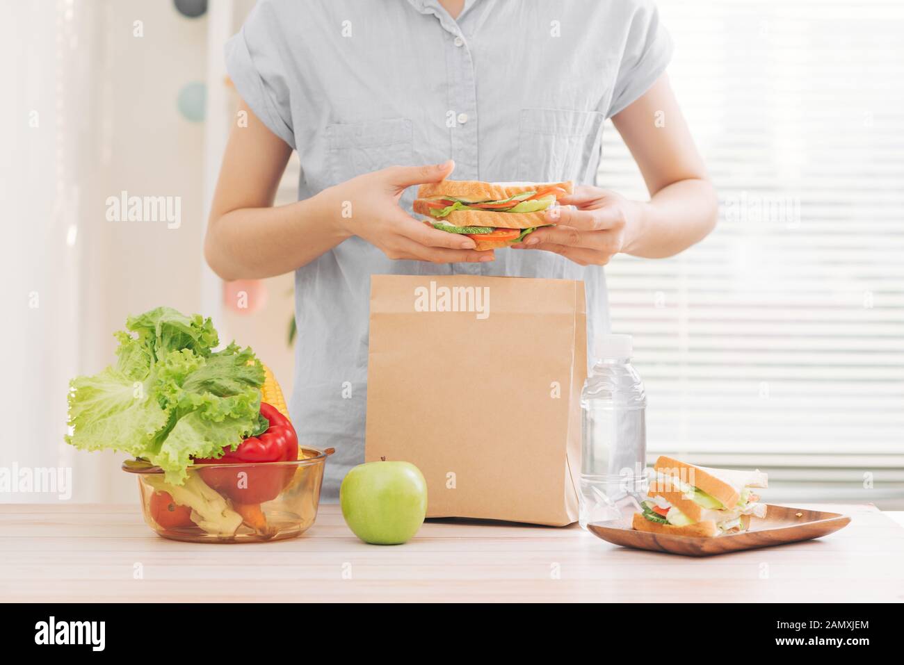 Mom preparing school snack or lunch for her daughter in home kitchen ...