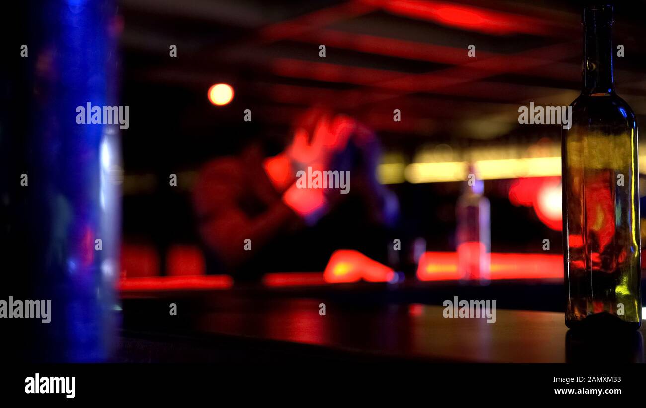 Depressed man drinking alone in nightclub, thinking over problems ...