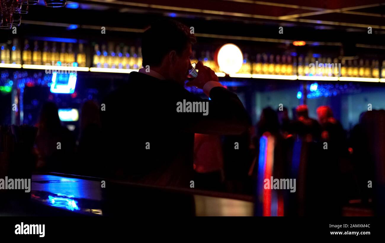 Man dancing alone at bar counter and drinking alcohol, watching people ...