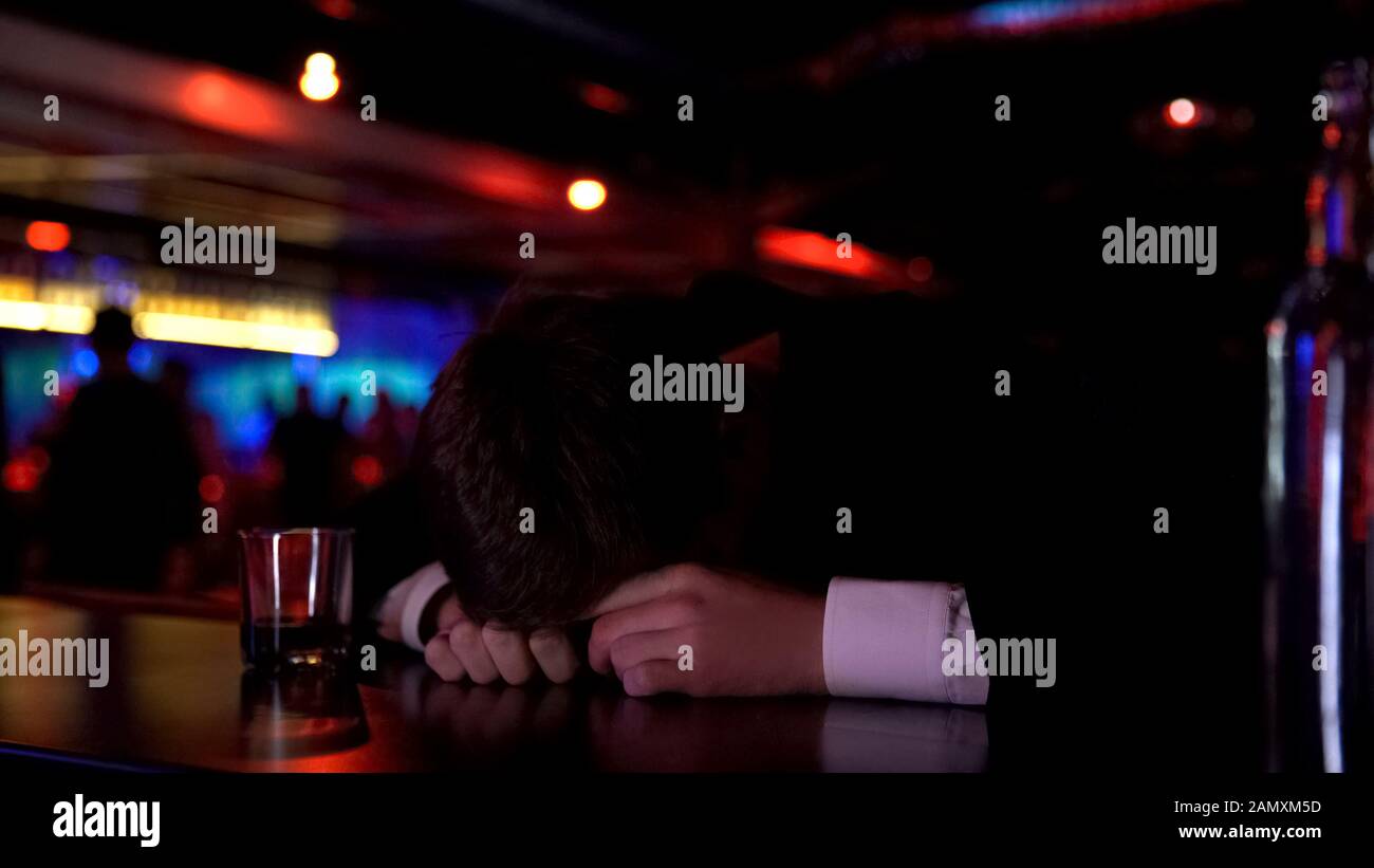 Drunk man sleeping on bar counter, suffering depression, alcohol abuse ...