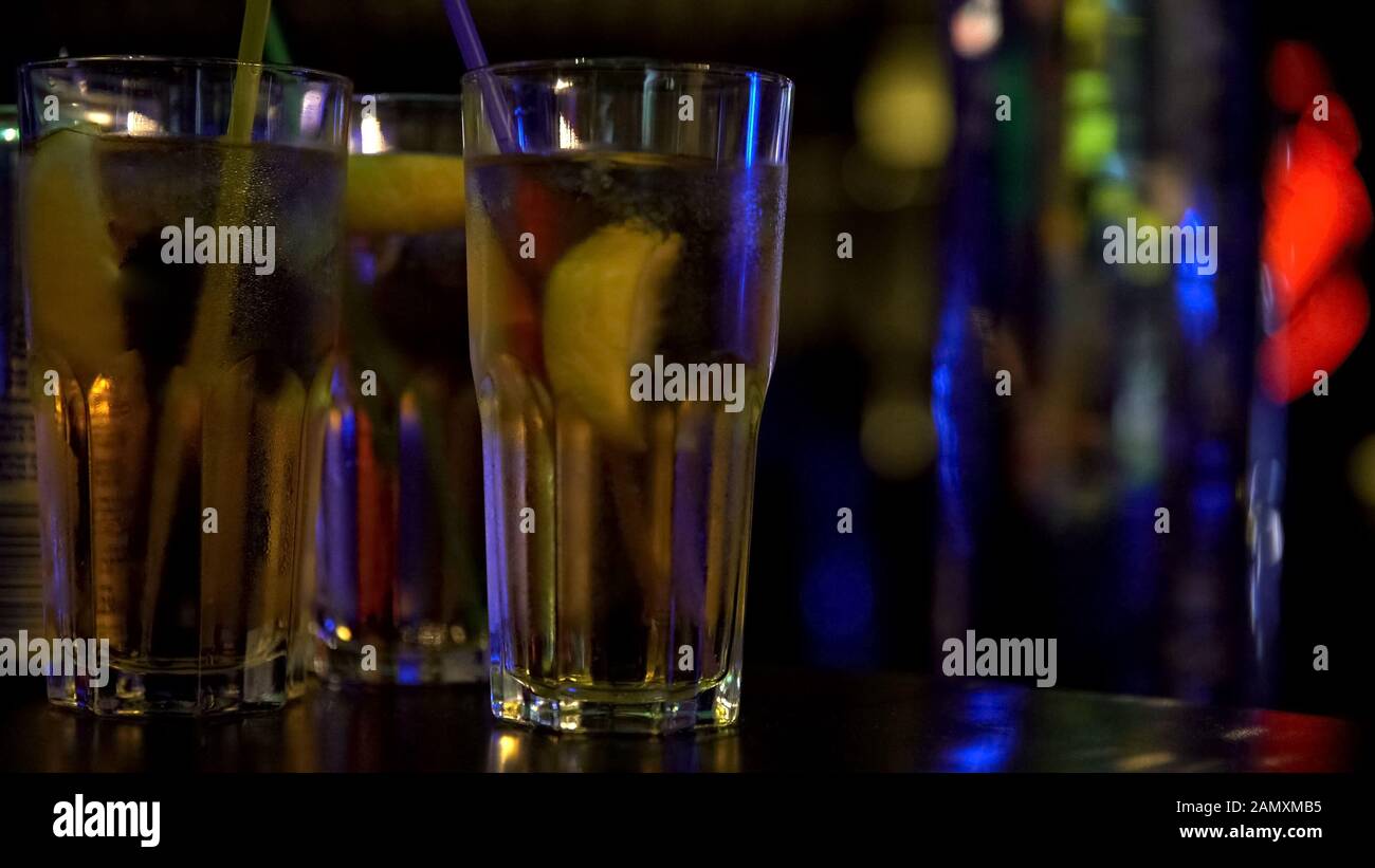 Glasses with alcoholic cocktails standing on bar counter at nightclub ...