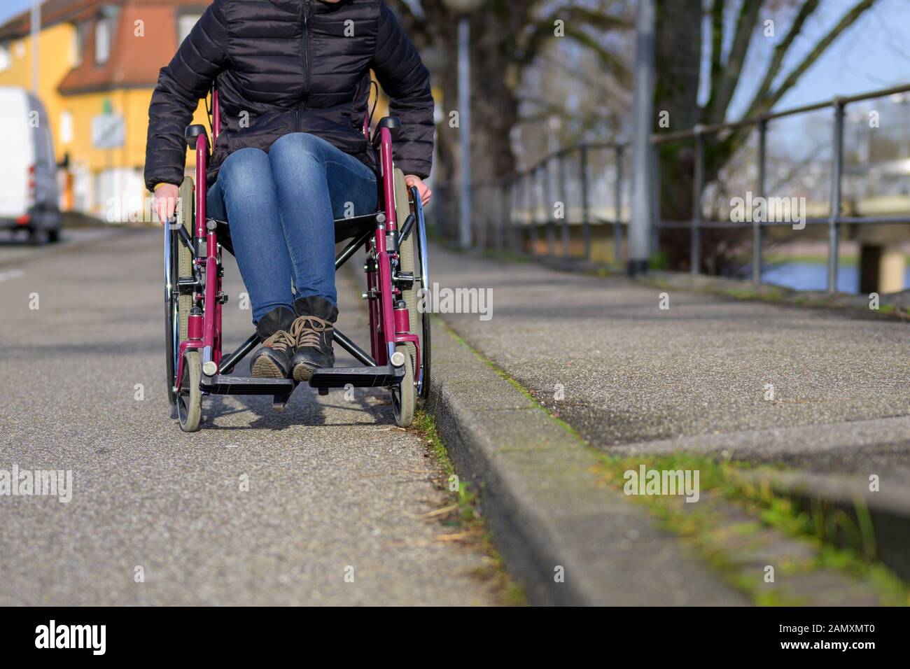 Feet of a disabled woman seated in a wheelchair at the edge of an urban ...