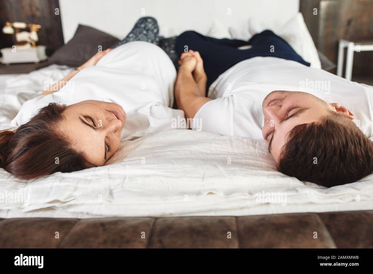 A young married couple awaiting a baby. Beautiful couple lying in the ...