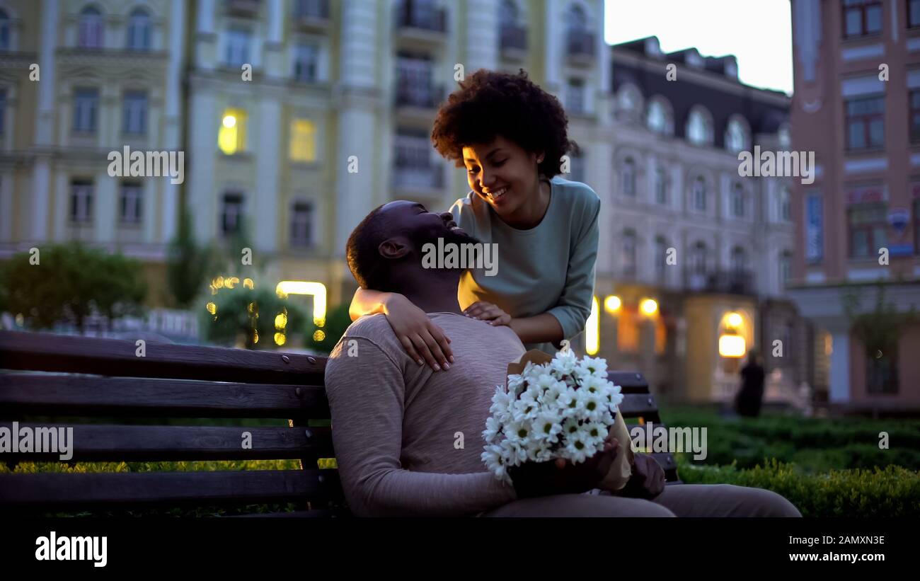 Woman hugging boyfriend, looking with love, holding flowers, romantic ...