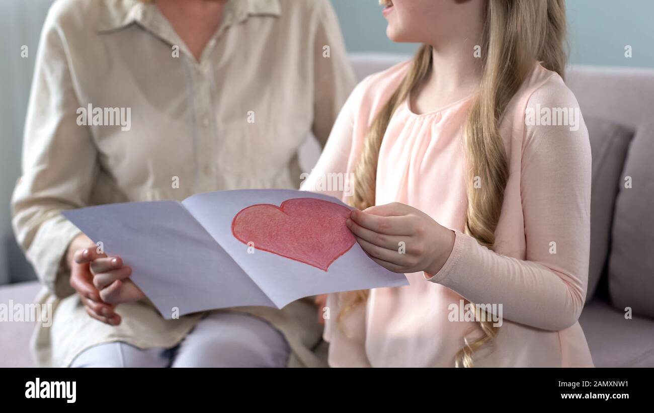 Cute little granddaughter presenting handmade greeting card to grandma ...