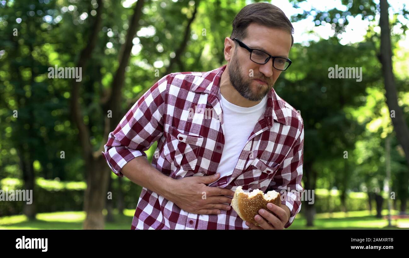 Male eating burger, feeling nausea, junk food poisoning, body ...