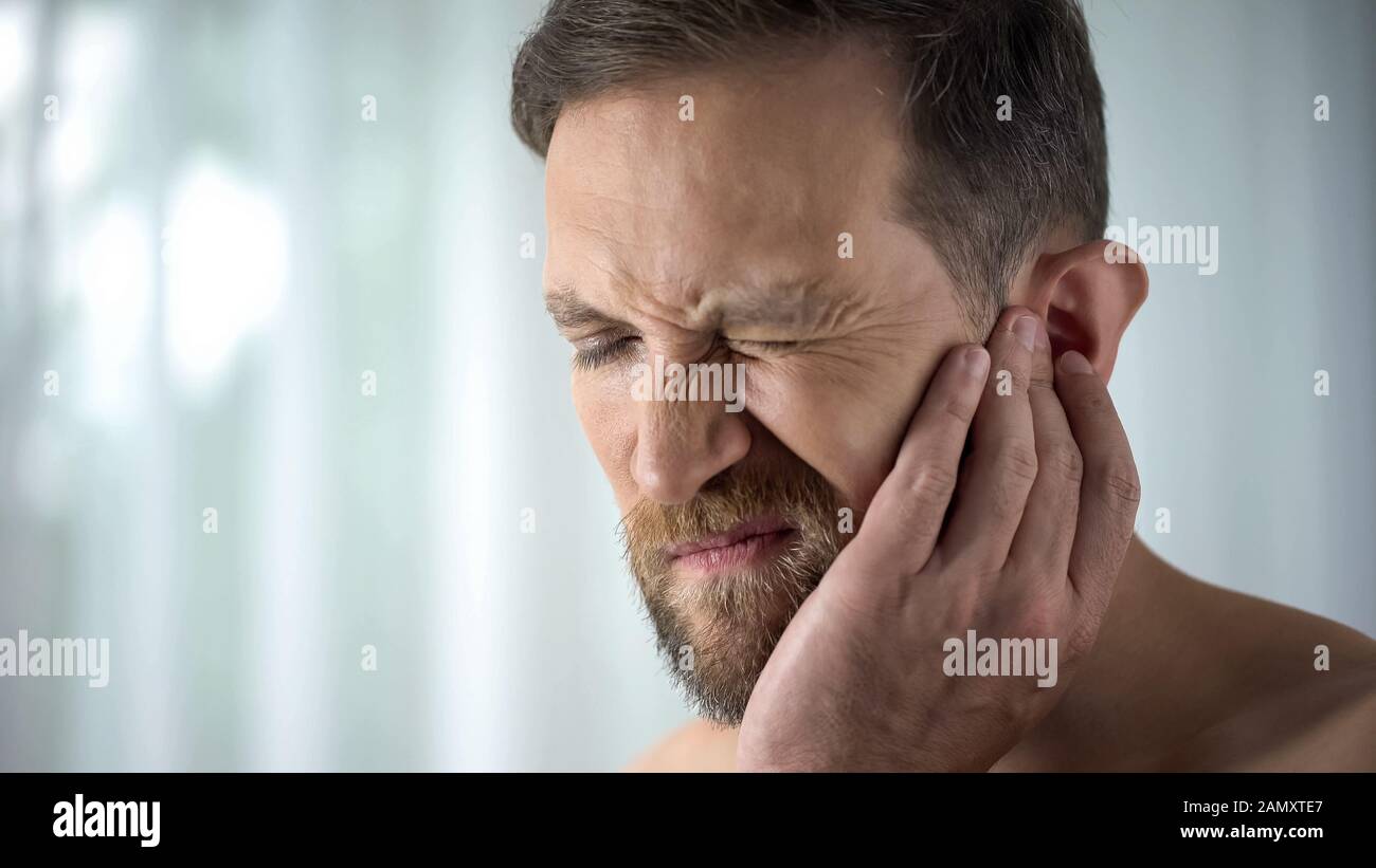 Male suffering from tooth ache, touching cheek, pulp inflammation ...
