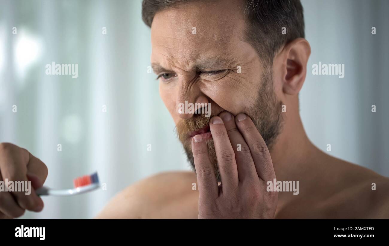 Caucasian man brushing teeth and seeing blood on toothbrush, dental ...