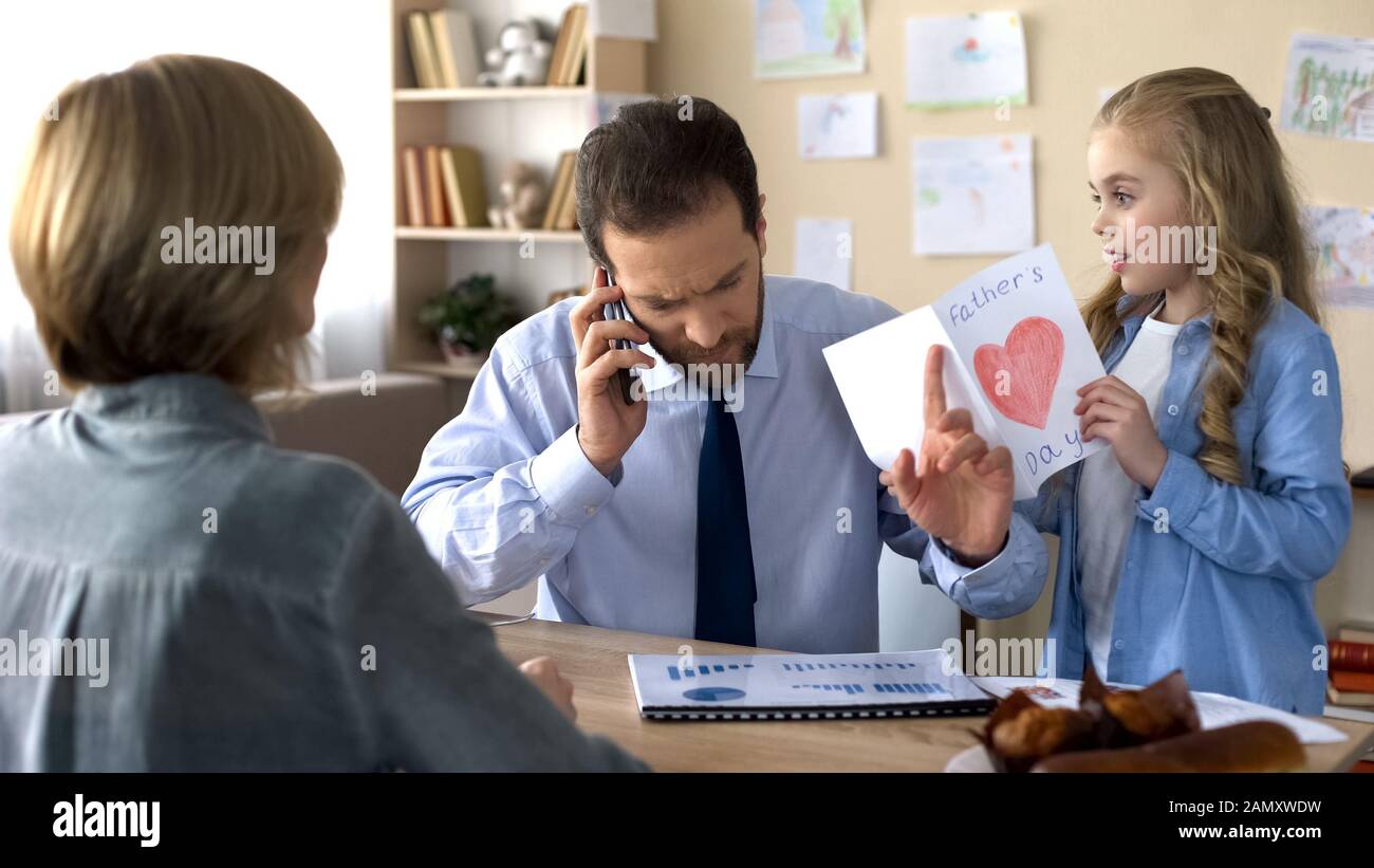 Father ignoring daughter with greeting card, talking on phone ...
