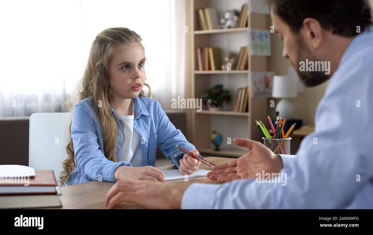 Demanding father making his little daughter doing homework, home ...