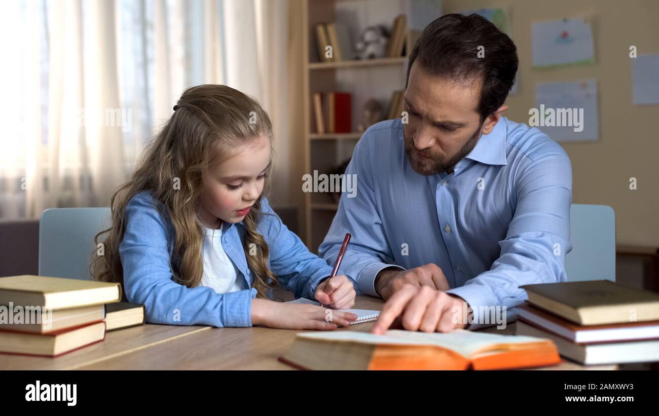 Attentive father helps his little daughter to do homework, education ...