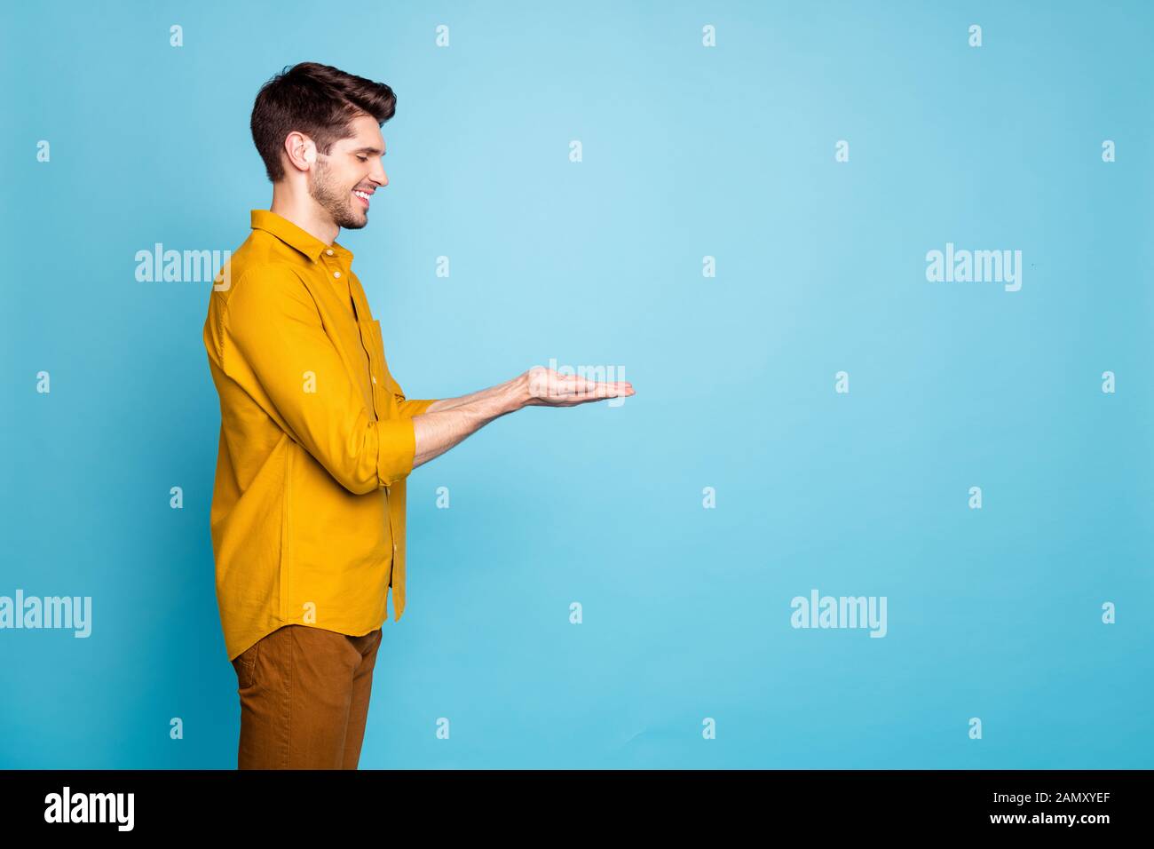 Photo of adoring man holding object with hands wearing yellow shirt ...