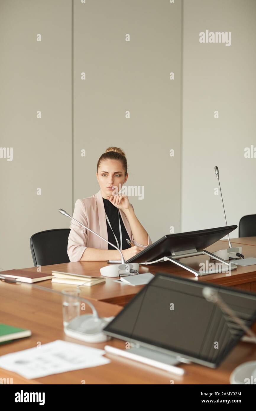 Serious female leader sitting at the table with pensive sight during ...