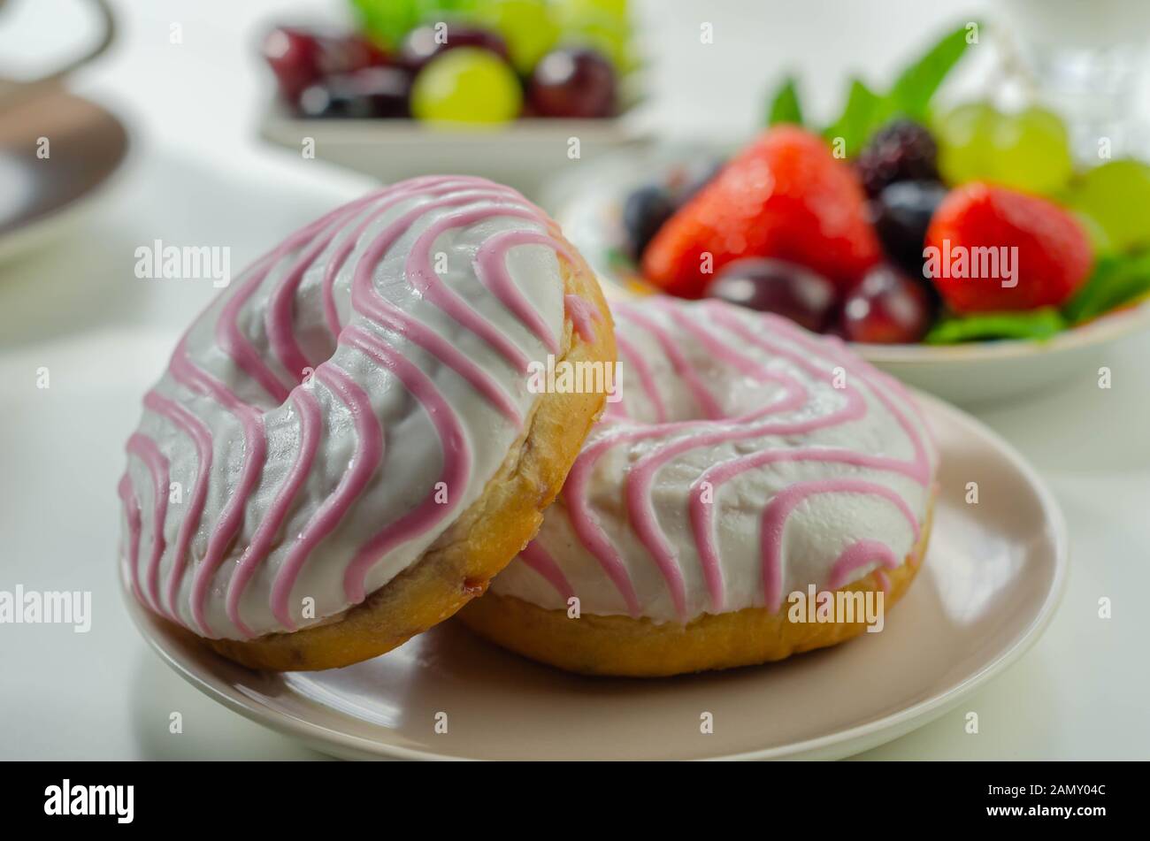 Doughnut with raspberry flavour filling, topped with white and pink ...