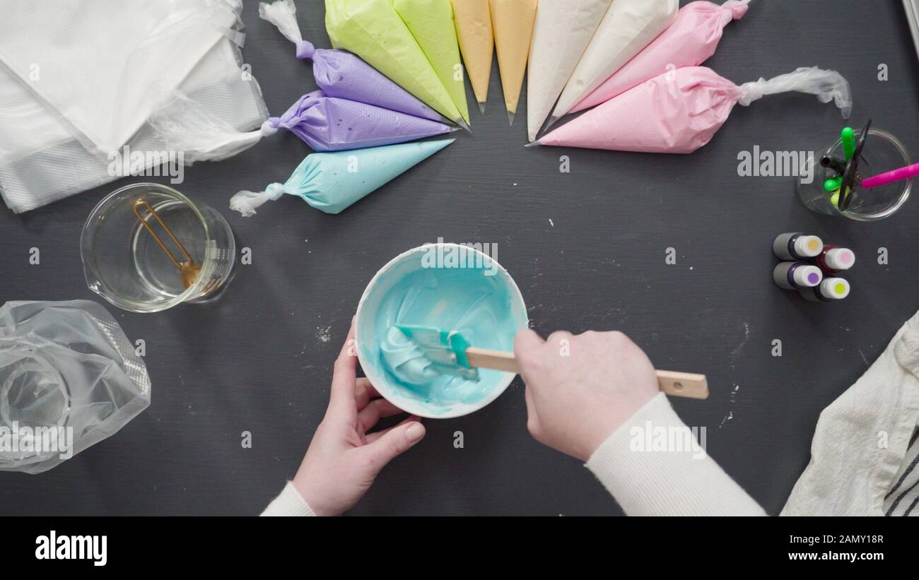 Step by step. Flat lay. Mixing in food coloring into the royal icing to ...
