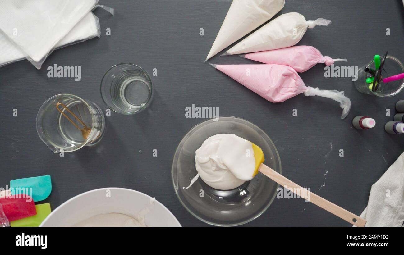 Step by step. Flat lay. Mixing in food coloring into the royal icing to ...