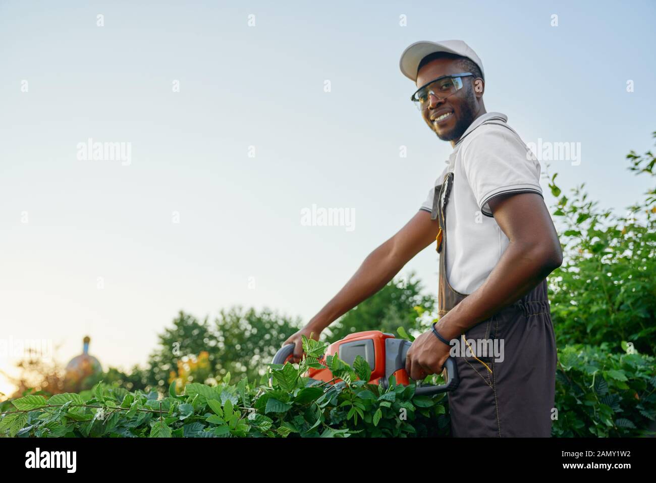 Happy african man in working clothing, summer hat and glasses smiling ...