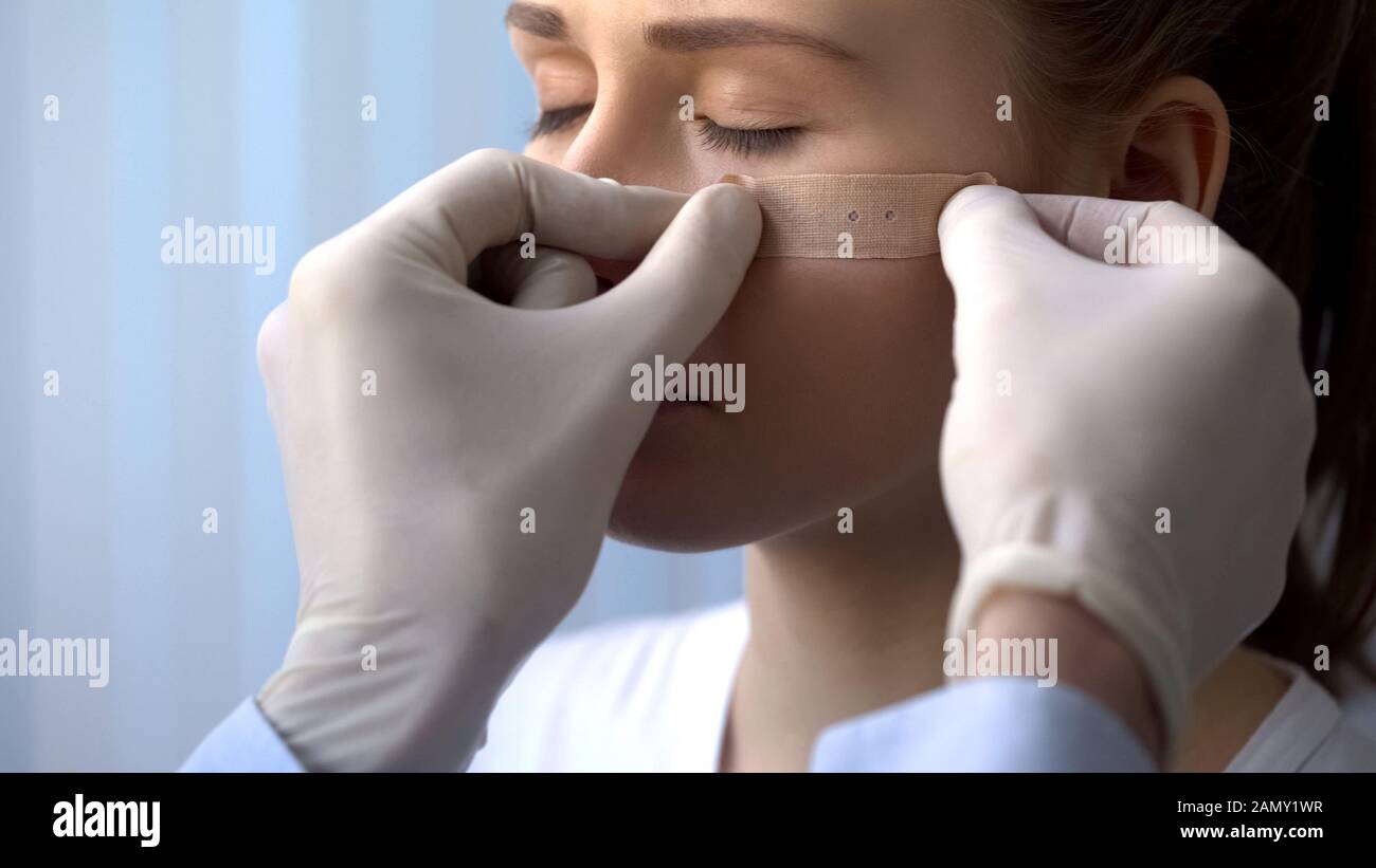 First aid measures, doctor putting patch on wounded female patient face ...