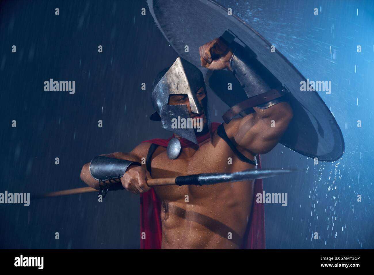 Front view of fearless muscular spartan hiding from rain under shield ...