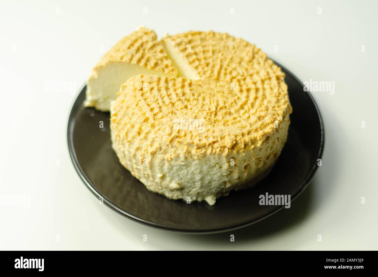 Smoked cottage cheese, brined cheese cut on a plate, a traditional and ...