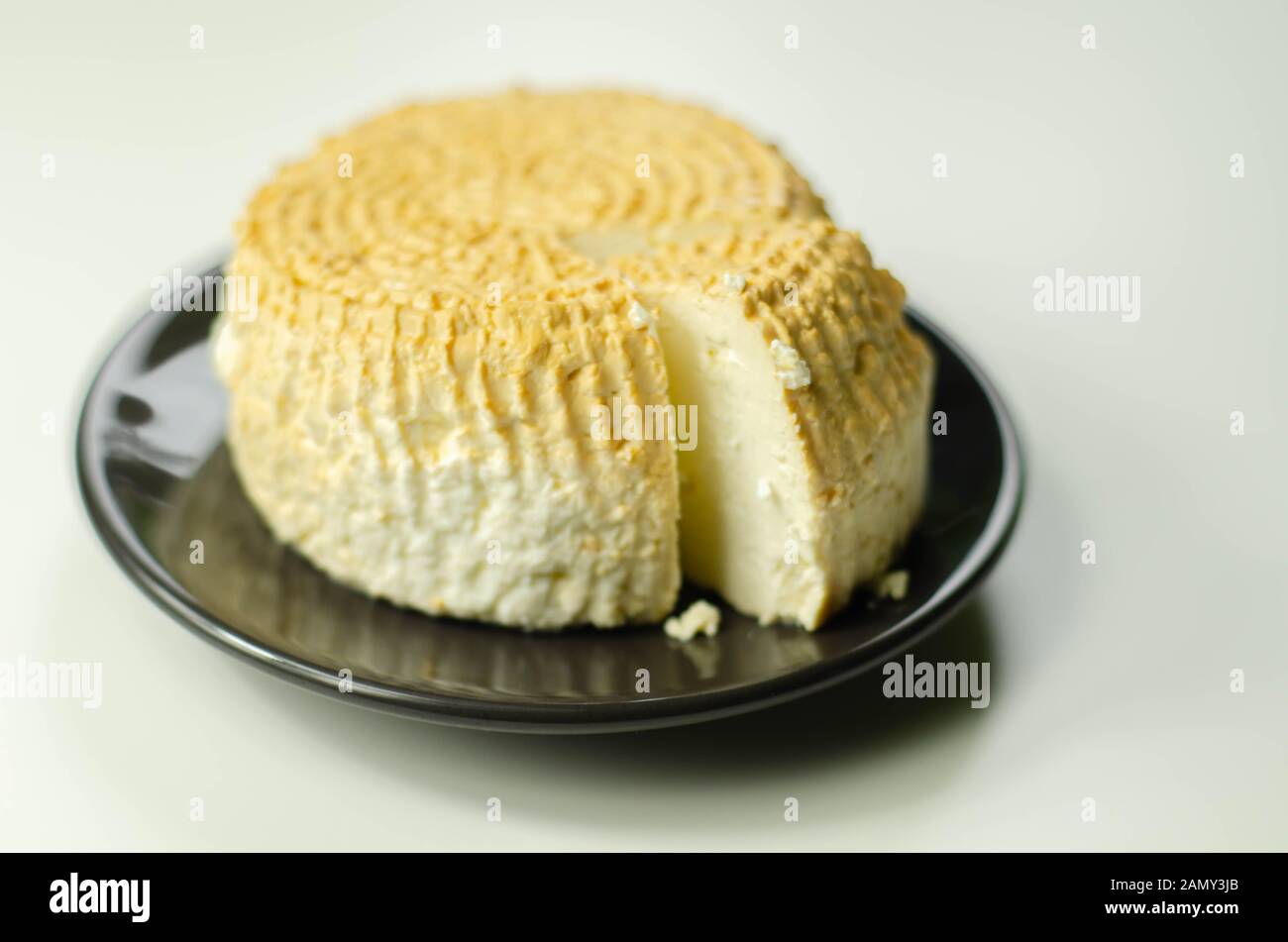 Smoked cottage cheese, brined cheese cut on a plate, a traditional and ...