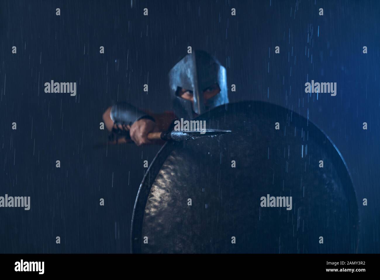 Portrait of spartan in armor fighting outdoors with spear. Front view ...